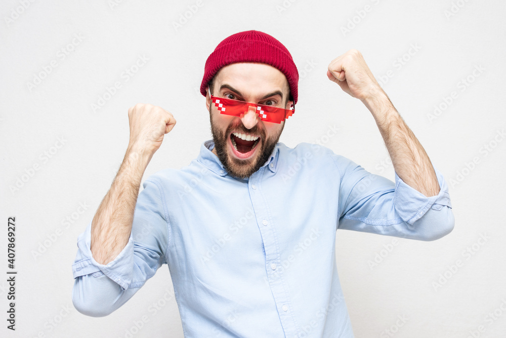 Attractive bearded man in red pixel glasses rejoices in the victory and ...