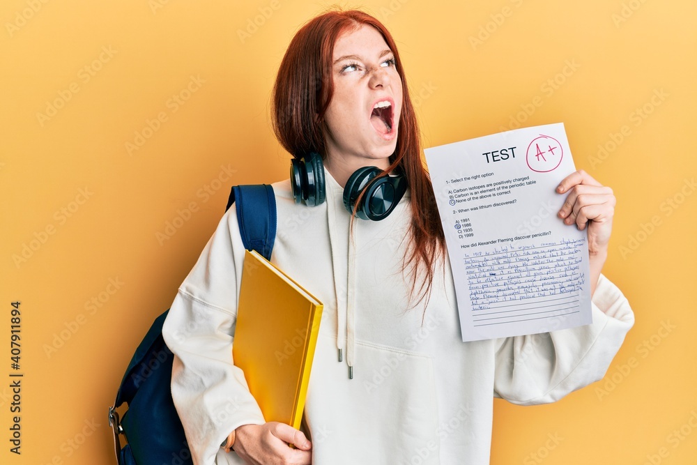 Young red head girl wearing student backpack holding passed test angry ...
