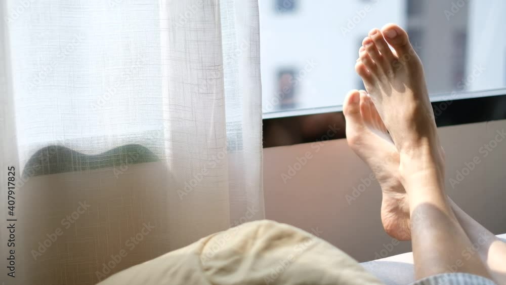 Women's feet Rhythmically Draped on a gray sofa late in the day Where ...