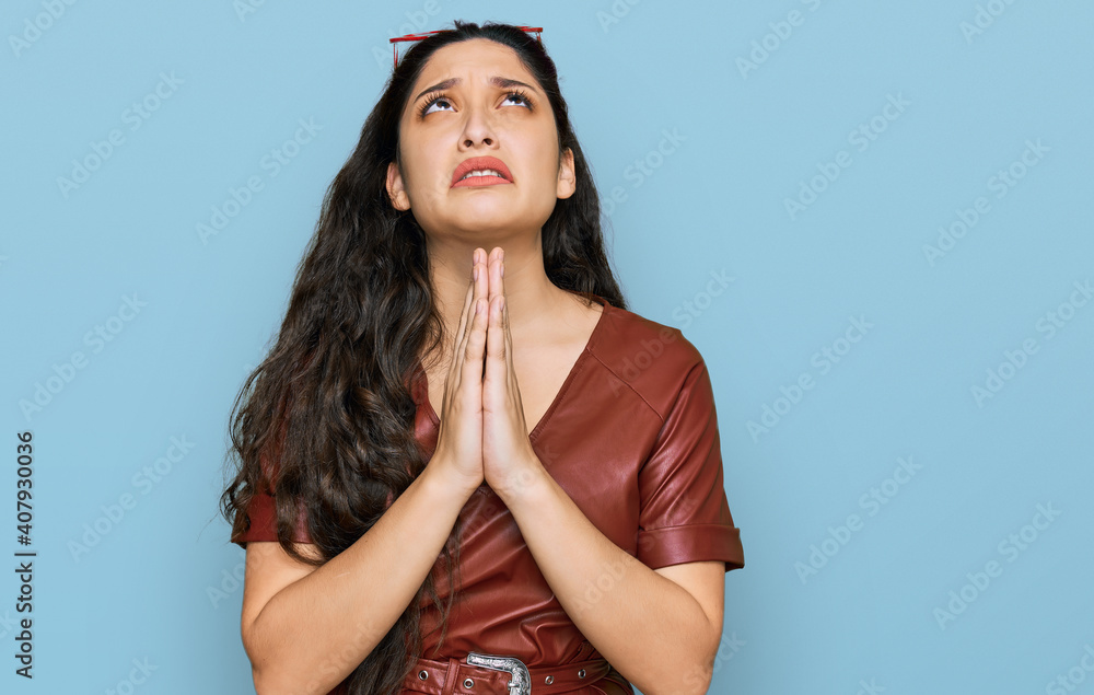Brunette young woman wearing dress and sunglasses begging and praying ...
