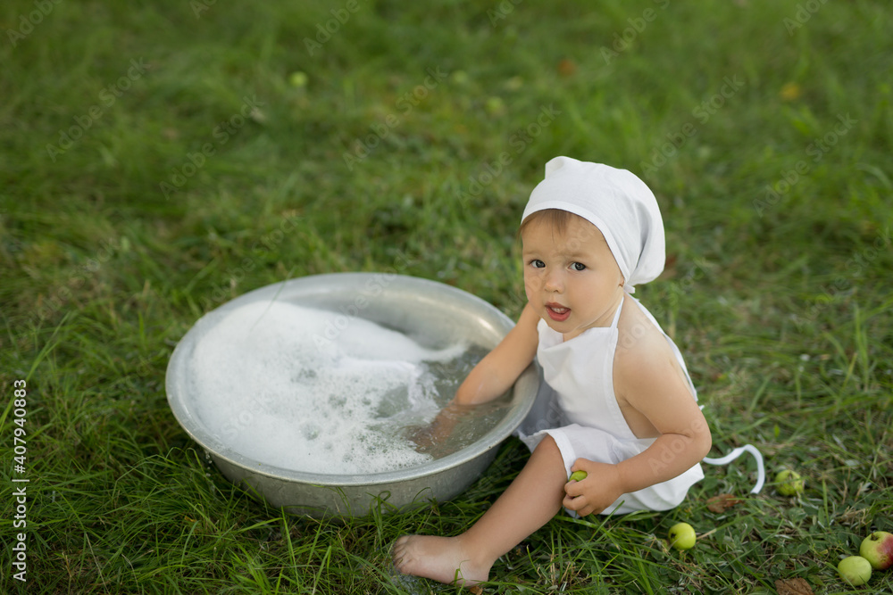 A child cheerfully launderes his clothes in the basin.Spray water and ...