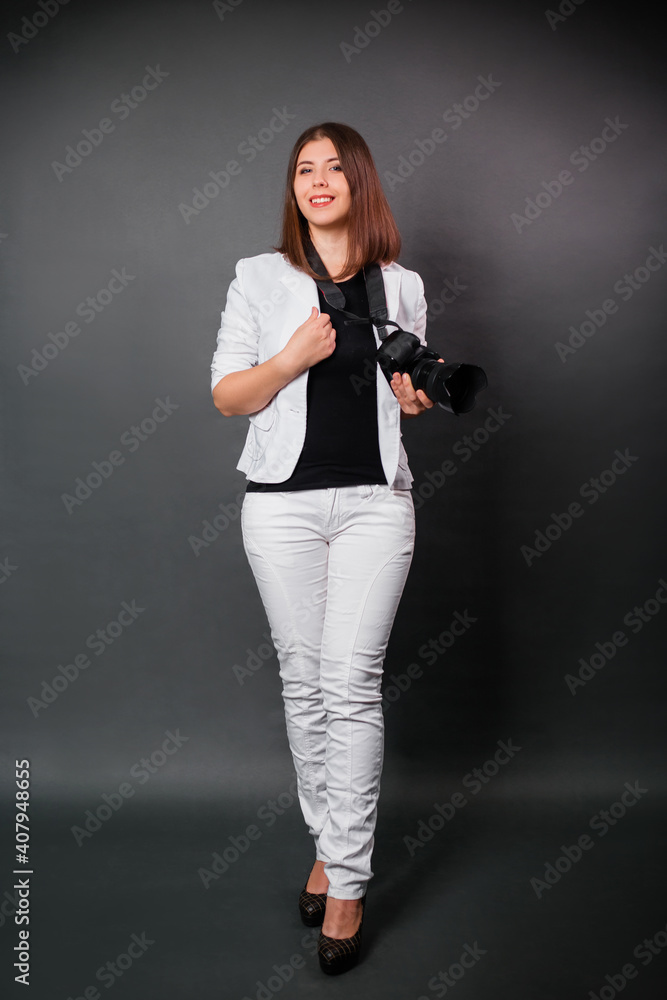 A woman in a white suit with a camera in her hands posing while ...