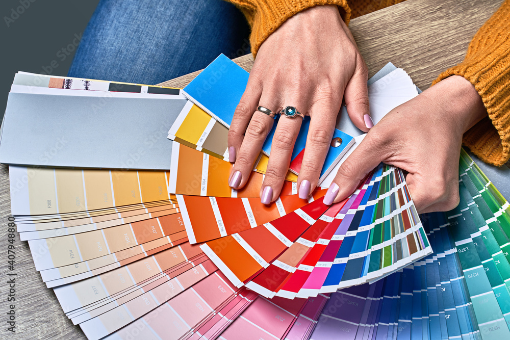 Color wheel for choosing paint tone. Hands of female interior designer ...