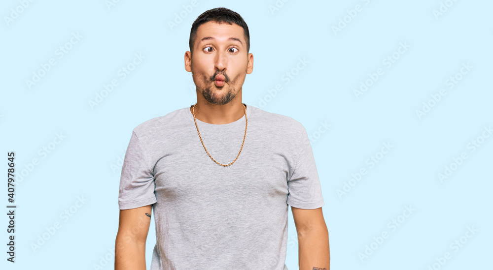 Handsome man with tattoos wearing 90s style making fish face with lips ...