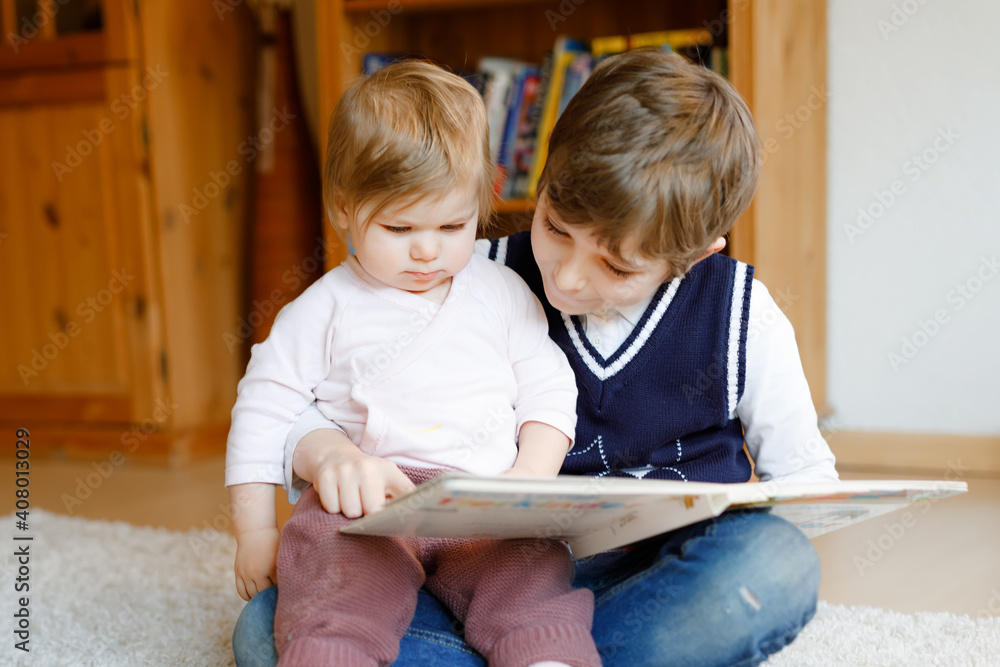 School kid boy reading book for little toddler baby girl, Two siblings ...