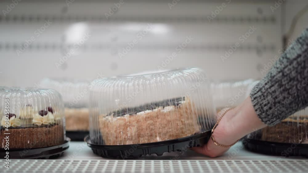 Showcase with delicious cakes packed in transparent plastic containers ...