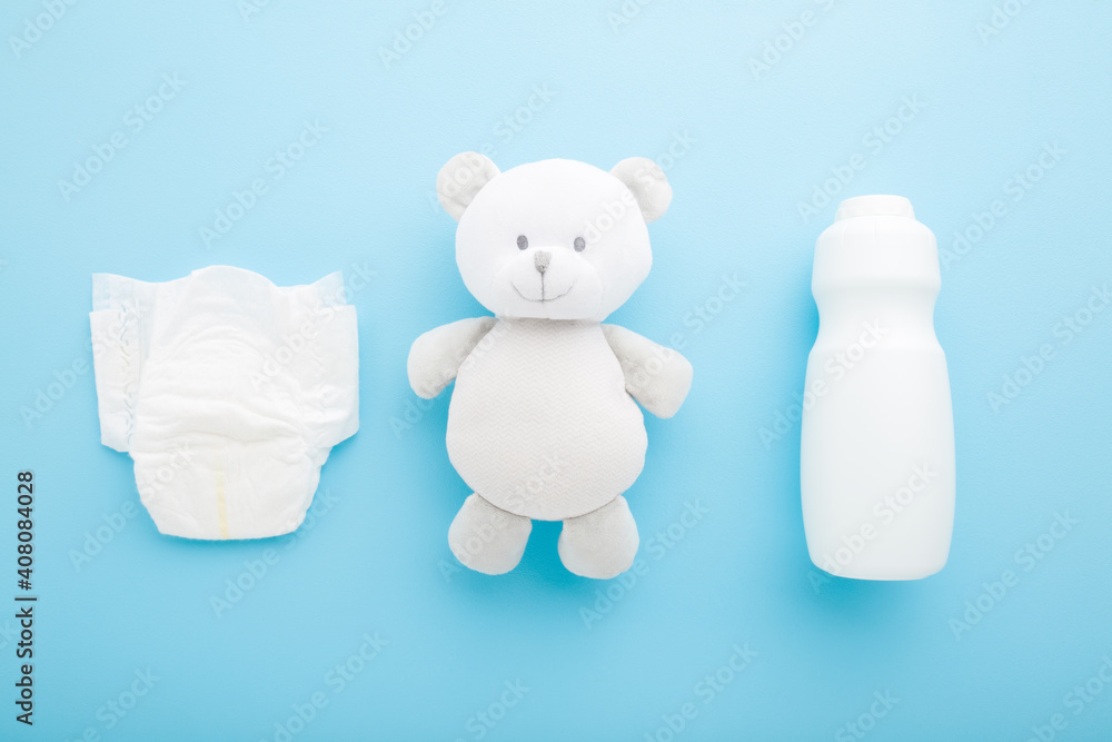 Teddy bear, white bottle of talcum powder and diaper on light blue ...
