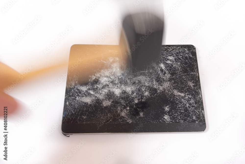 A smashed digital tablet is laying isolated on white and is about to be ...