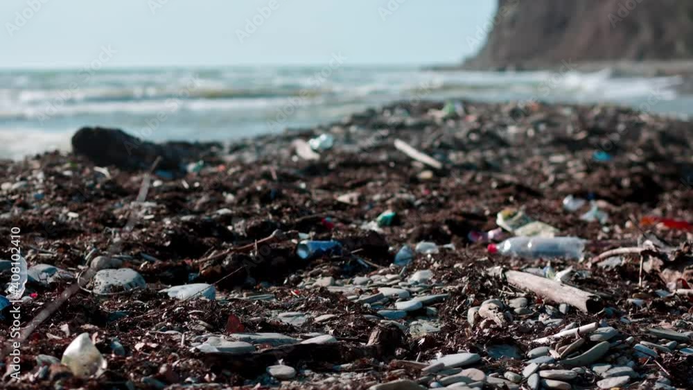 Dirty ocean shore after a storm, seaweed and plastic garbage. Moving ...