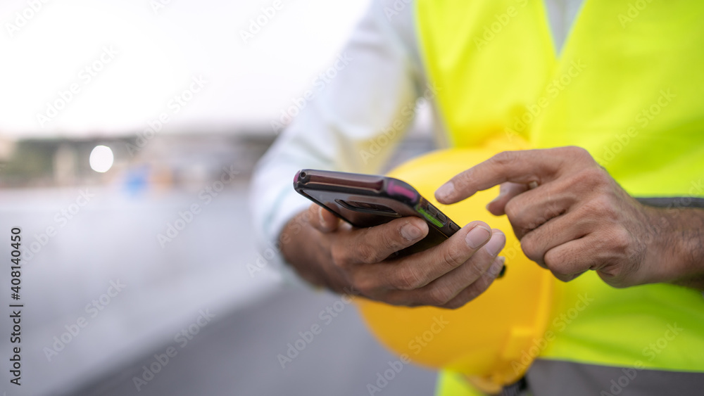 construction working touch screen on his smartphone at the construction ...