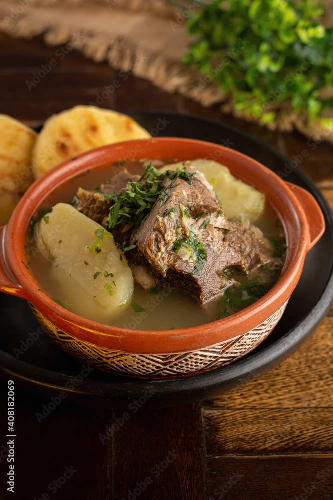 Foto de Caldo de costilla con papa pastusa arepa y cilantro en un plato ...