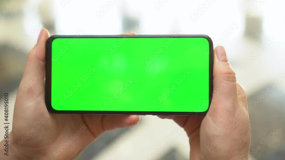 Back view of brunette holding chroma key green screen smartphone ...