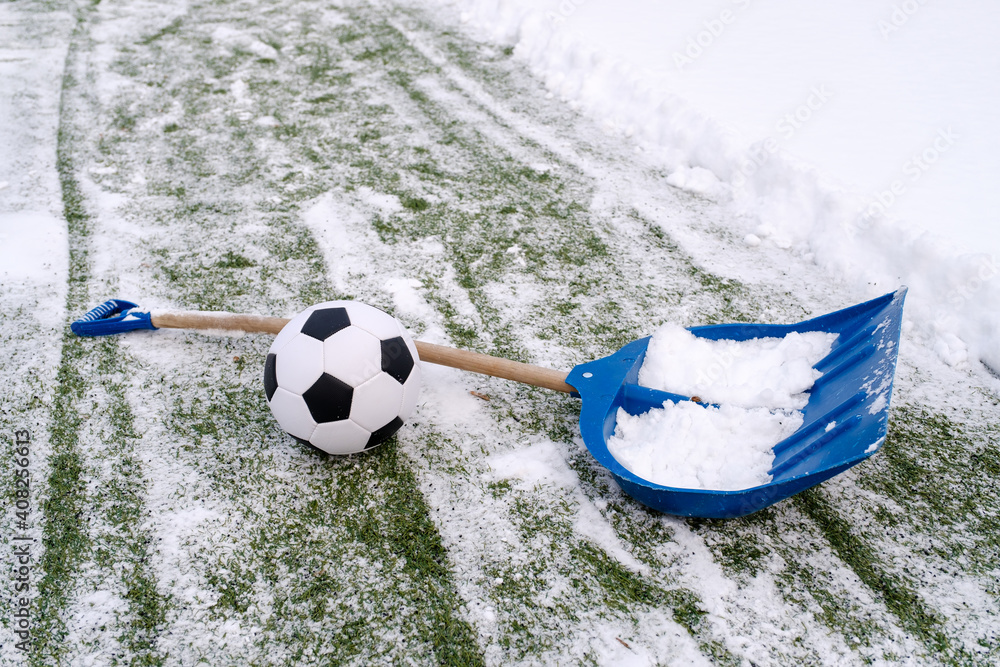 Shovel and classic soccer ball placed on snowy artificial grass of ...