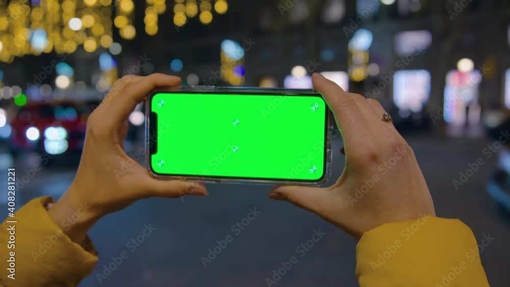 Woman hold smartphone with green screen. Background of busy bustling ...