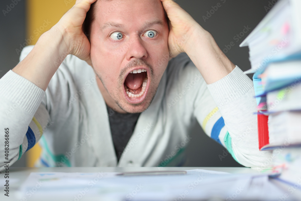 Dumbfounded man holds his head and looks at the stack of folders Stock ...