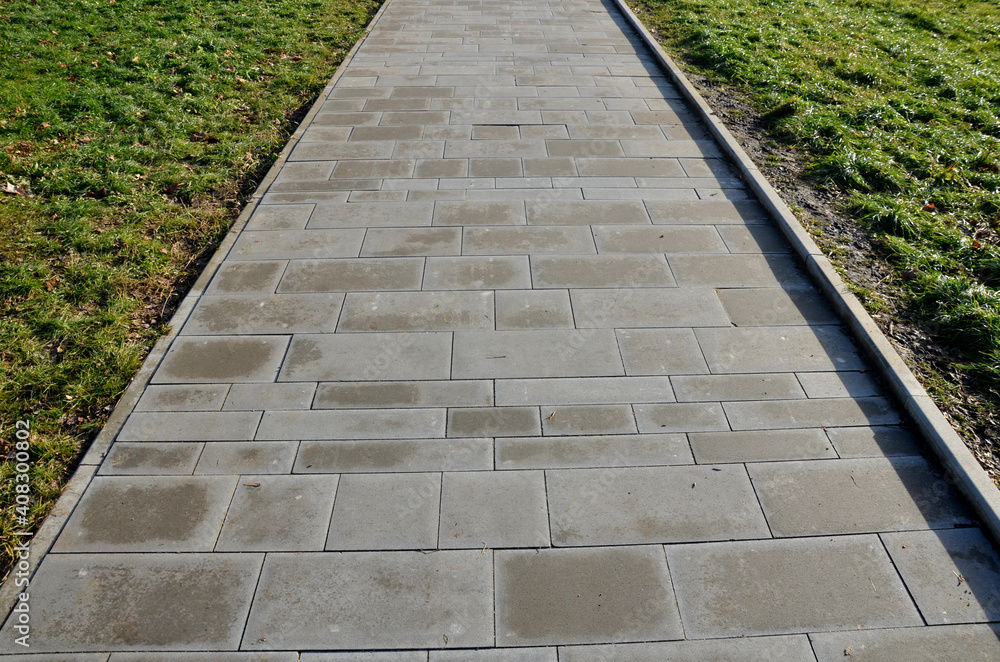 brown, gray concrete park path, curb on one side. tiles of different ...