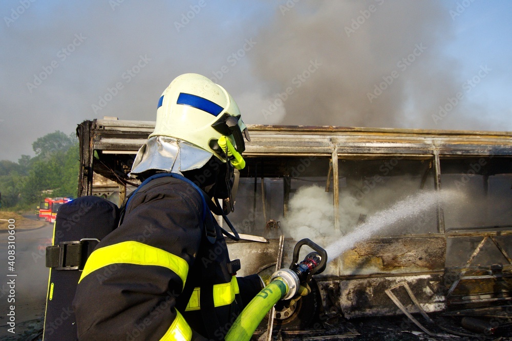 Firefighter in a helmet extinguishes a massive fire of several public ...