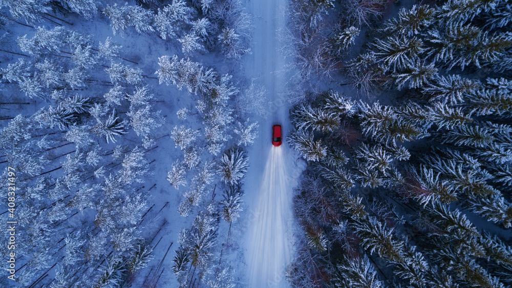 Winter landscape with red car driving at night. Lights of car and ...