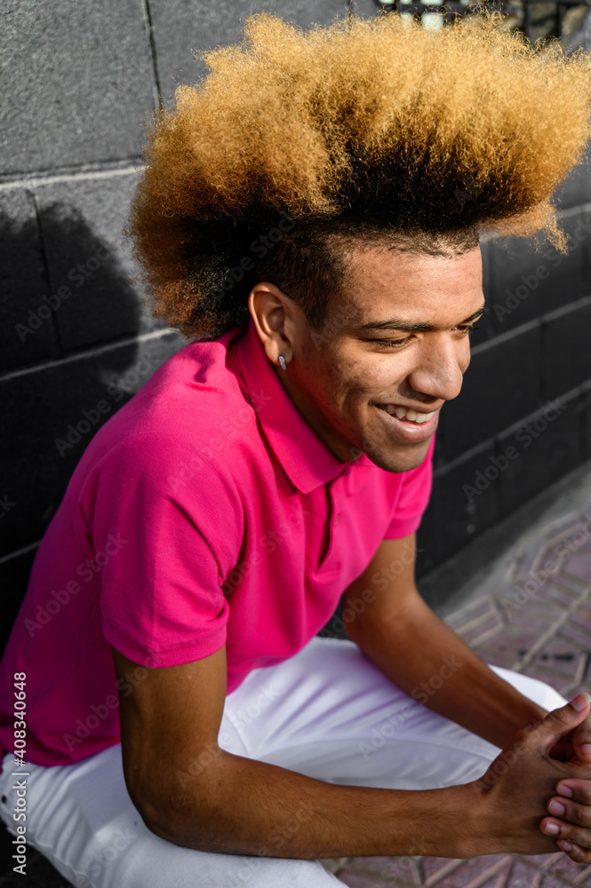 Hombre joven latino, moreno con pelo rizado a lo afro sentado en un ...
