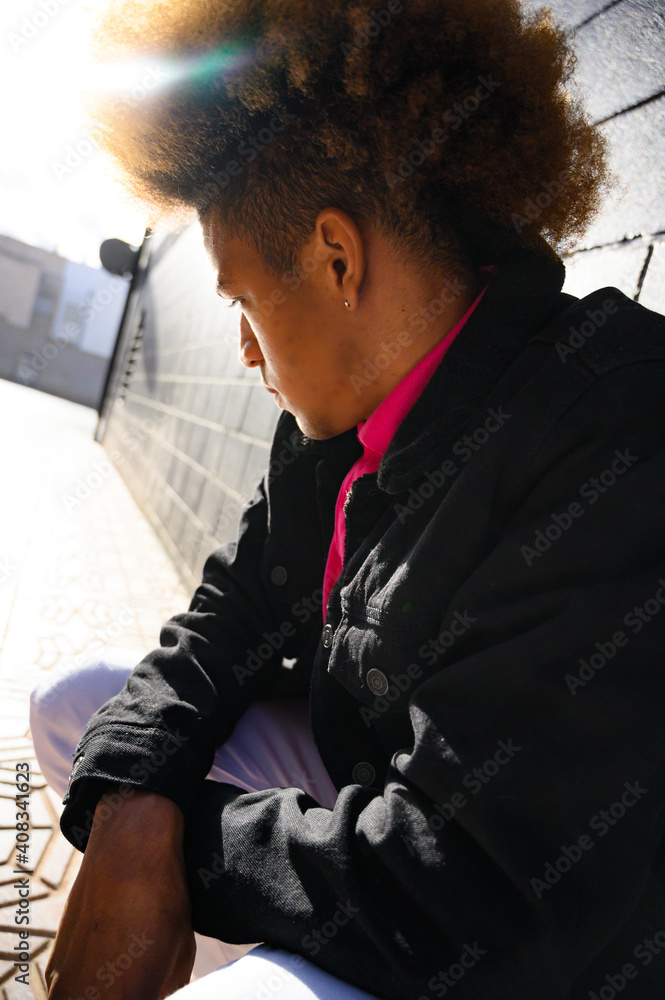 Hombre joven latino, moreno con pelo rizado a lo afro sentado en un ...