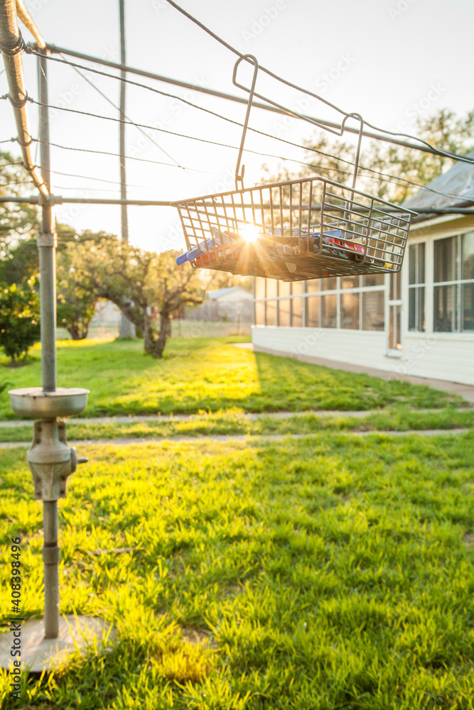 Sunlight shining through peg basket on washing line in backyard of ...