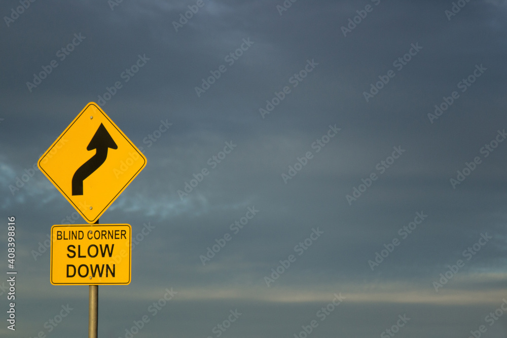 Blind corner slow down road sign against dark clouds Stock Photo ...