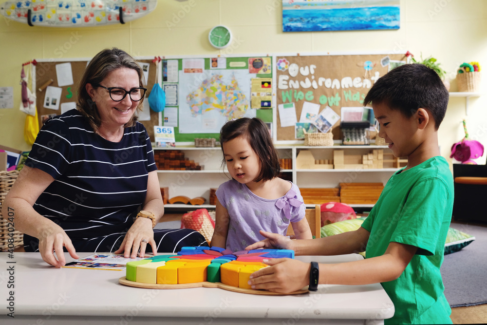 Multicultural teacher and children playing wooden blocks puzzles in ...