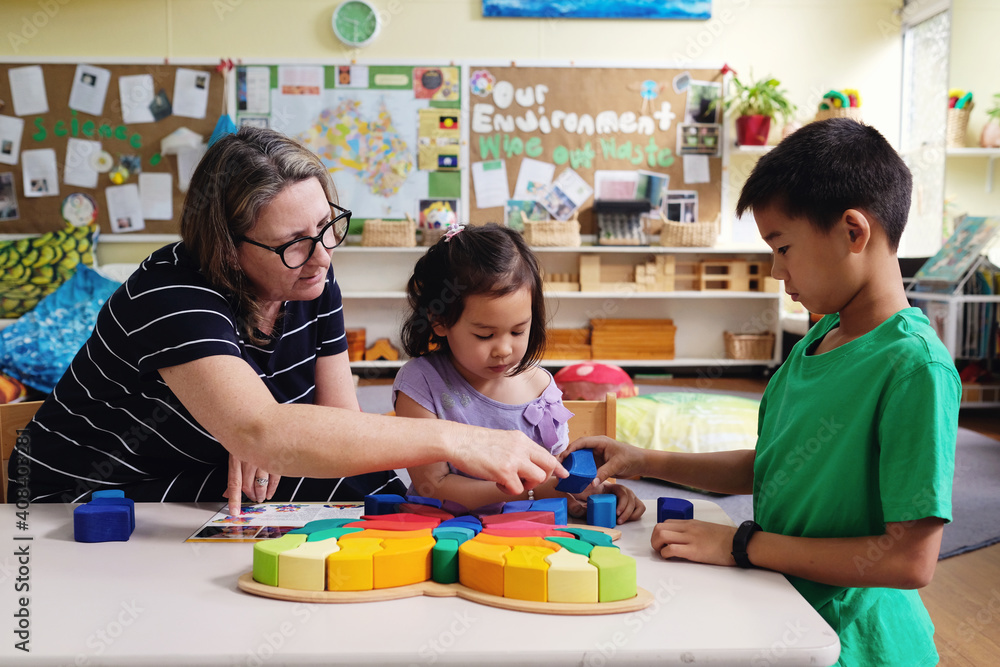 Multicultural teacher and children playing wooden blocks puzzles in ...