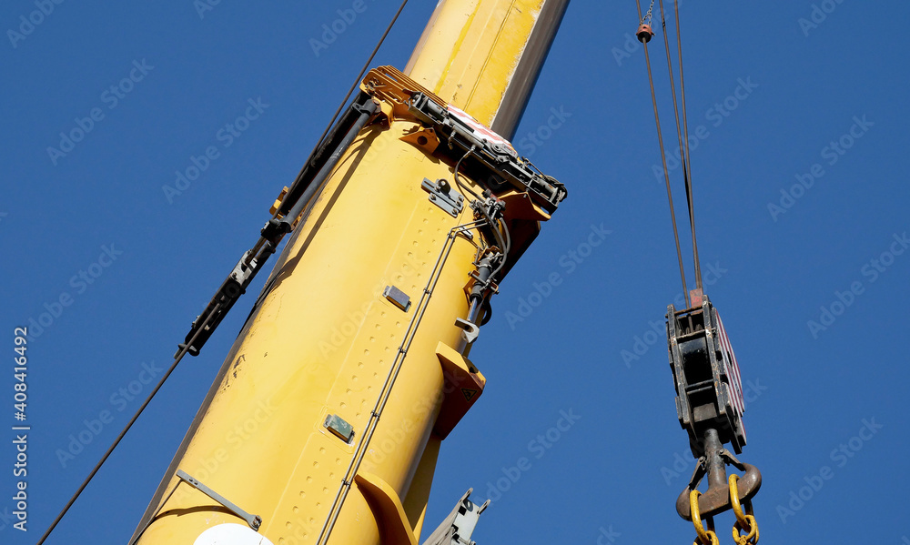 The yellow mechanical arm of a self-propelled crane with suspended hook ...
