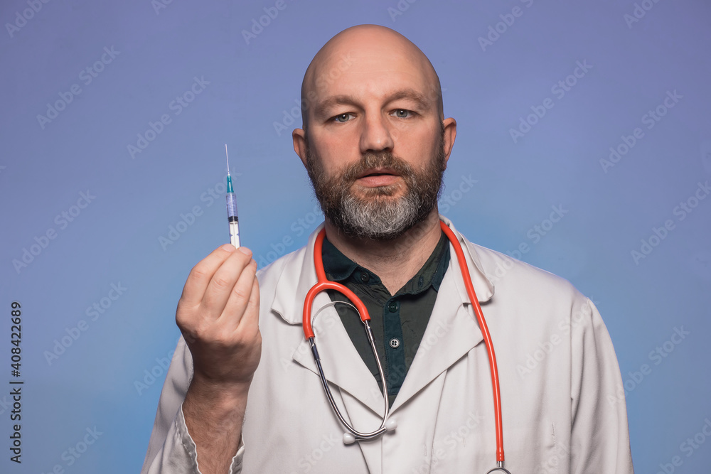 Studio shot of a bald doctor with beard in his 40s, holding syringe in ...