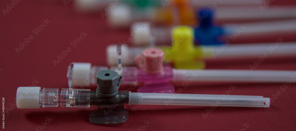 intravenous catheters on a red background, shot close-up. multicolored ...
