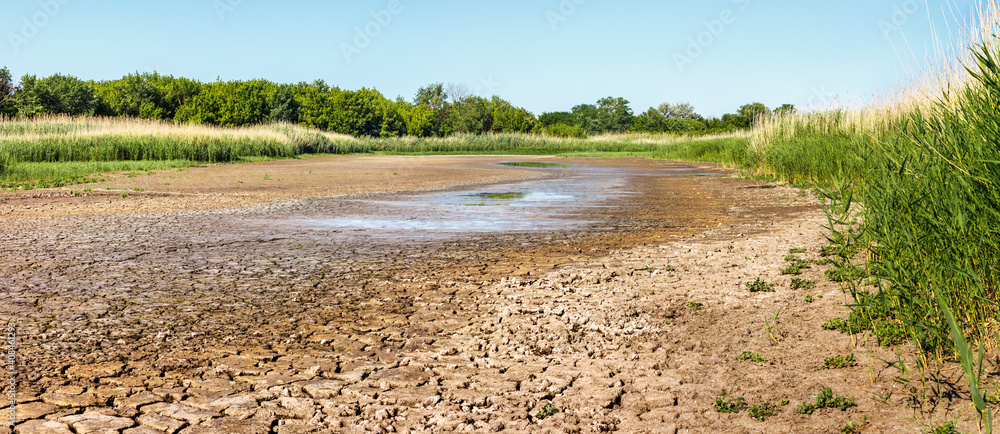 Dry riverbed with water remnant in puddles and cracked soil in hot ...