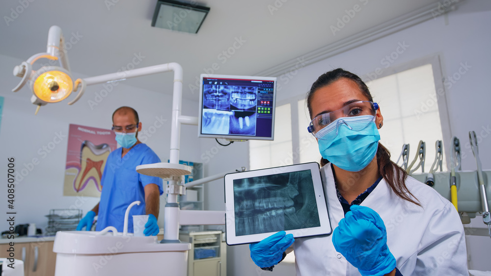 Dentist showing on tablet teeth x-ray reviewing it with patient. Doctor ...