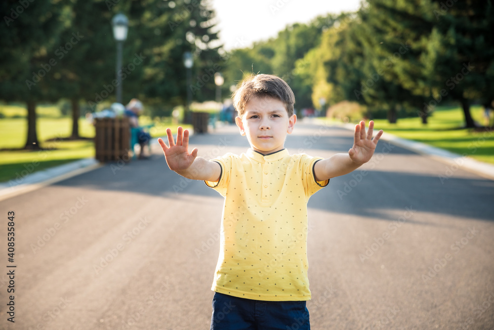 Happy child making a stop sign with his hand while standing at the road ...