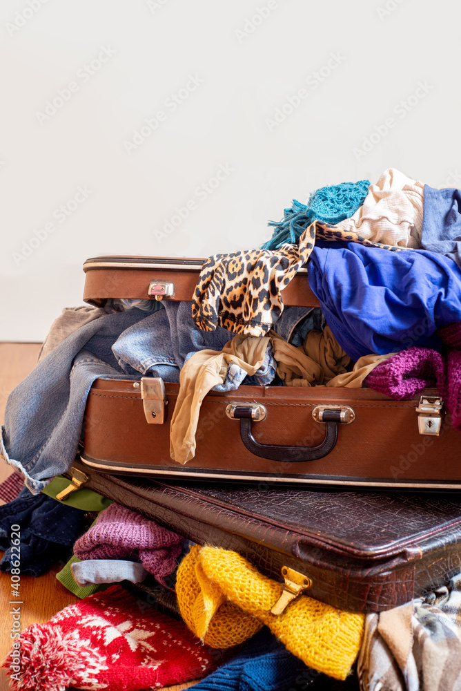 Old suitcases overflowing with second-hand clothes on the floor ...