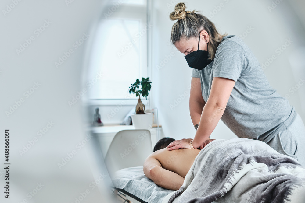 Foto de Young physiotherapist woman giving a massage to a young man ...