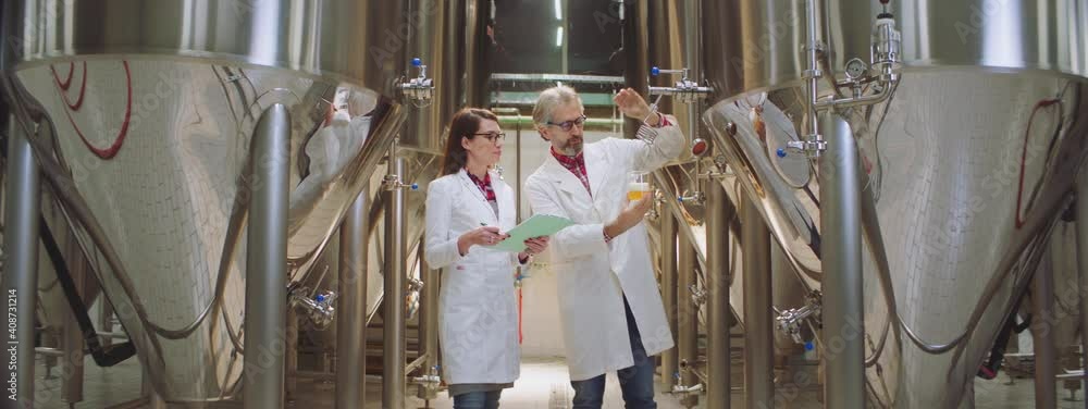 Two quality brewing experts discussing a beer sample and taking notes ...