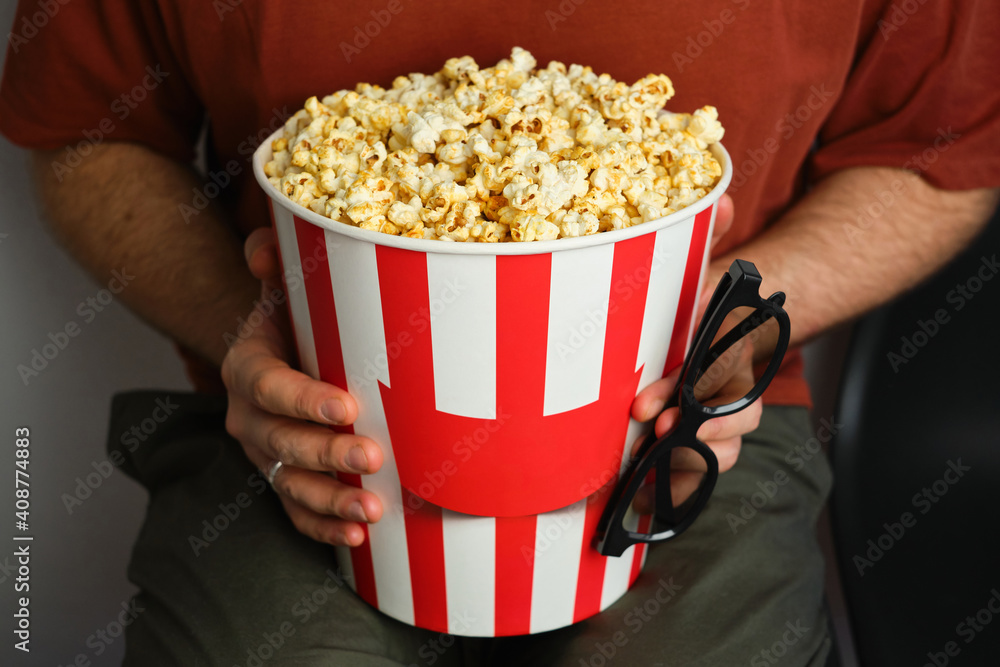Popcorn paper bucket and 3D glasses in the hands of a men preparing to ...