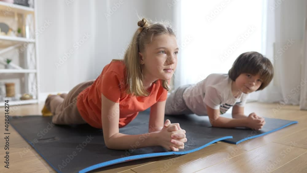Two concentrated fit Caucasian children in plank position at home ...