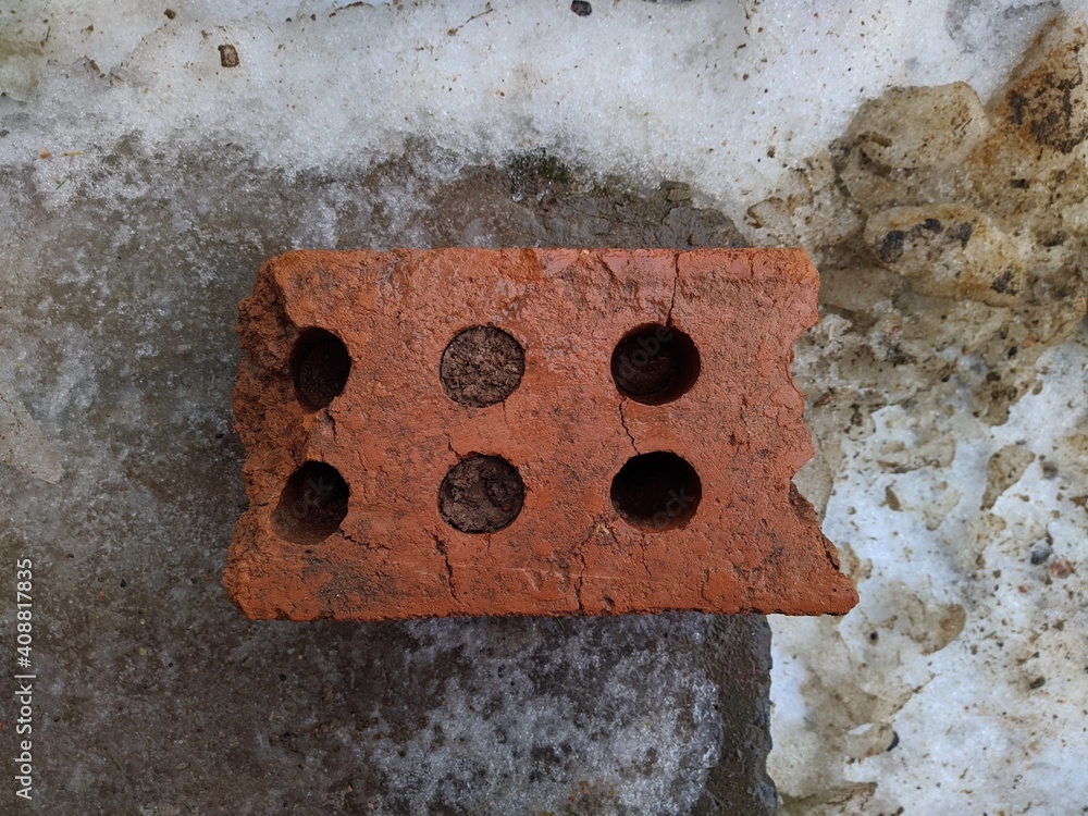 one dirty old and broken red brick lying on the street in the winter ...