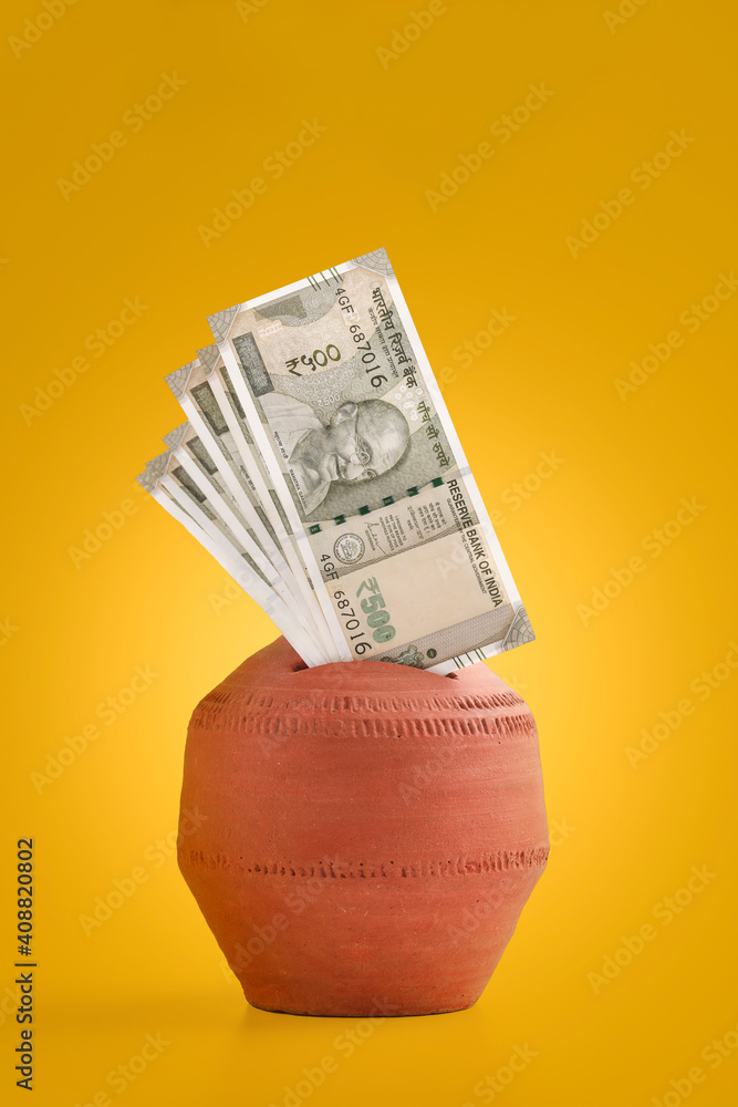 Clay piggy bank pot with five hundred rupees bank note in indian ...