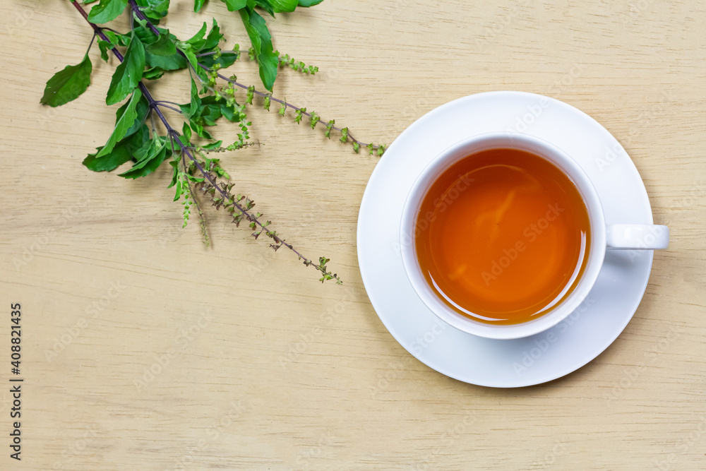 Tulsi or holy basil tea in white cup with fresh tulsi branch on wooden ...