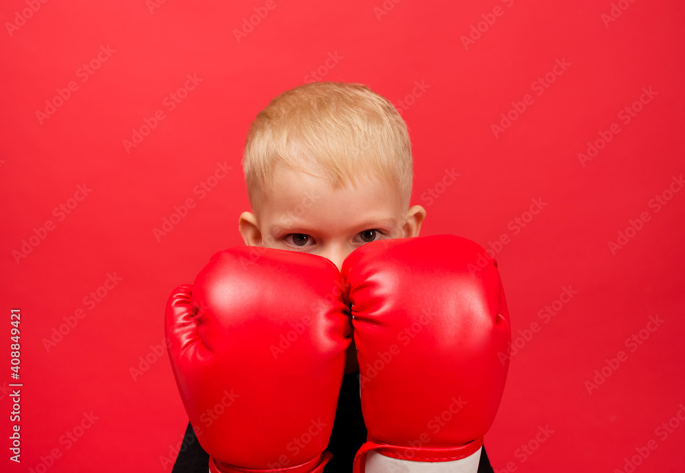 portrait of a boy boxer in red boxing gloves. The boy covered his face ...