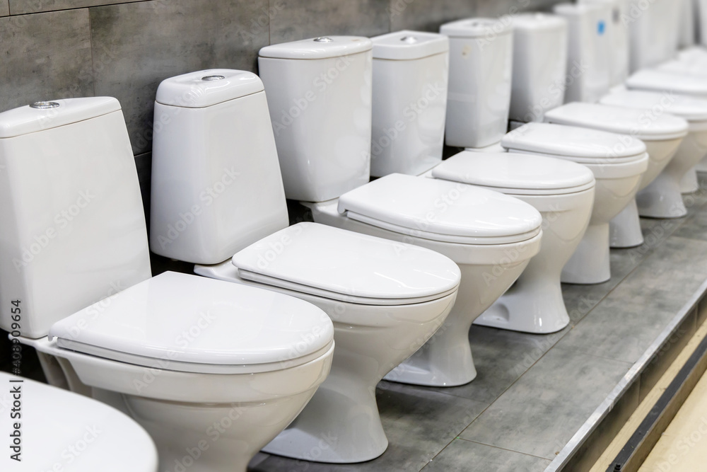 Diagonal row of modern new white toilet bowls in a plumbing store ...