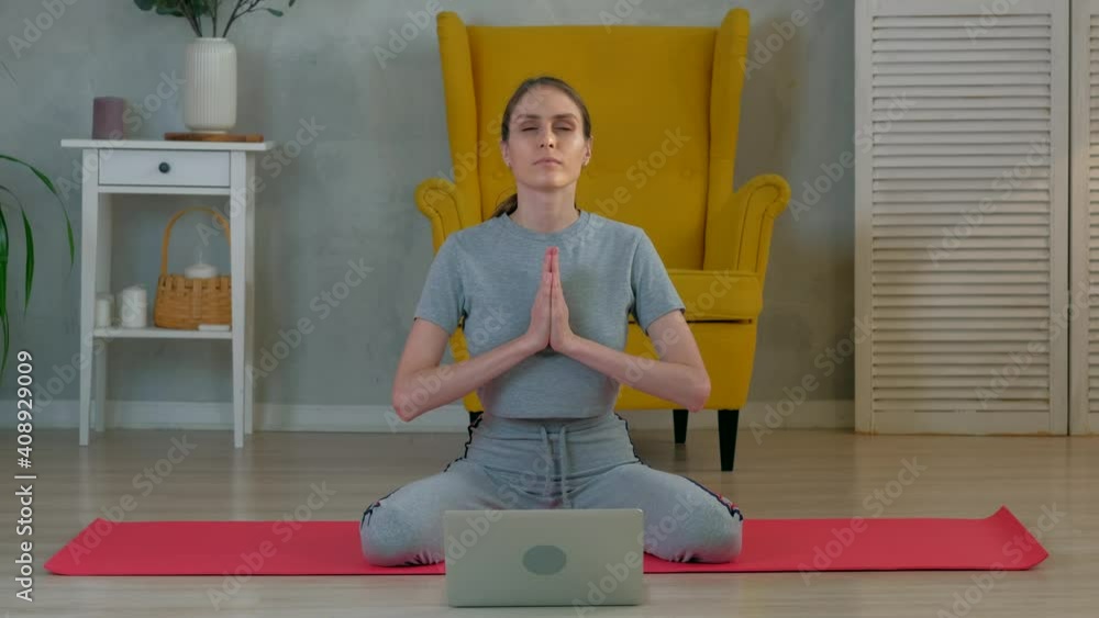 Relaxed woman with sporty body, sits in zen pose, keeps legs crossed ...