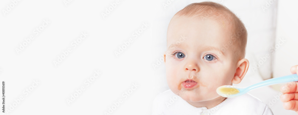 Caucasian baby boy face with spoon. Banner. Close up. First baby food ...