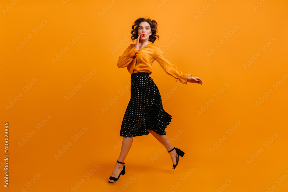 Excited woman dancing in long skirt. Surprised girl running on yellow ...