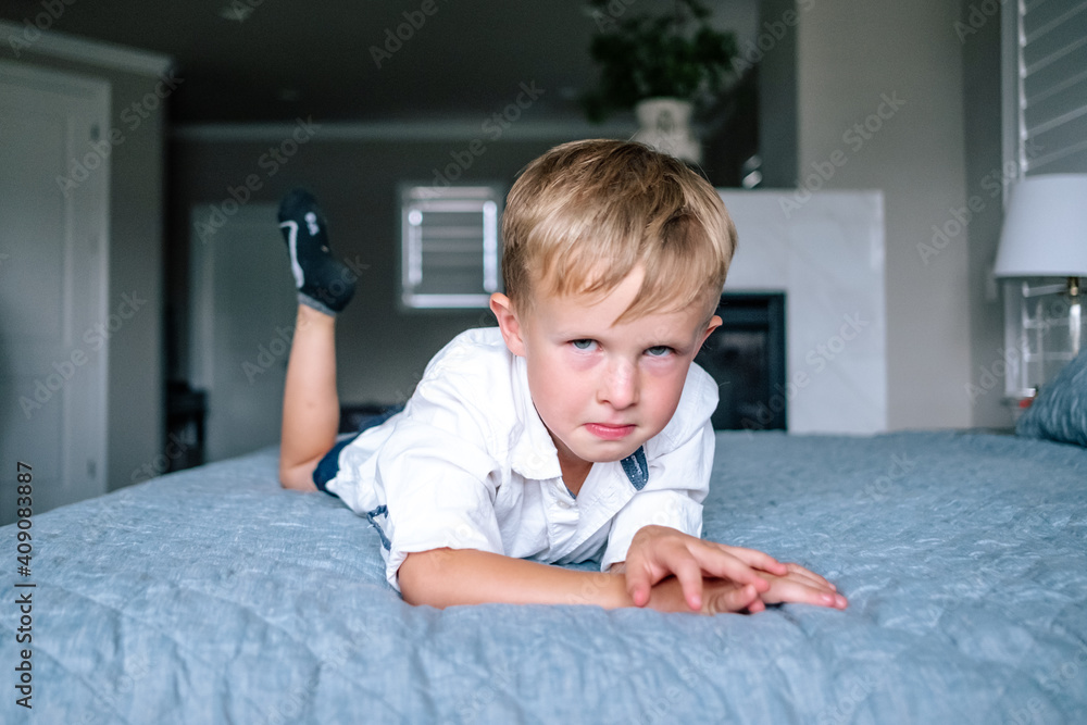 Preschool aged boy with angry face laying on a large bed Stock Photo ...