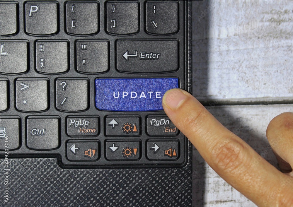 Finger pressing a blue key labeled UPDATE with symbol on a computer ...
