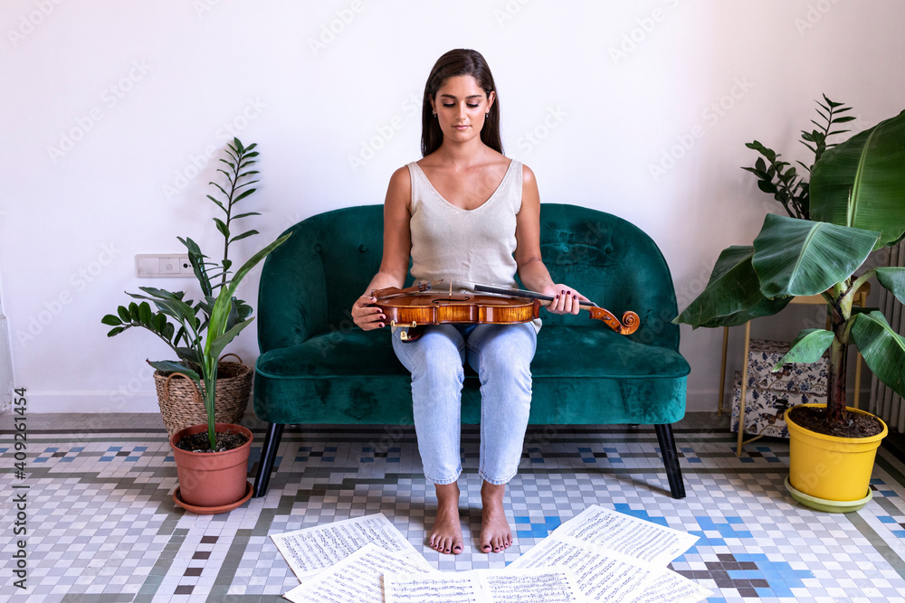 Sitting girl holding a viola, sheet music surrounding her bare feet ...